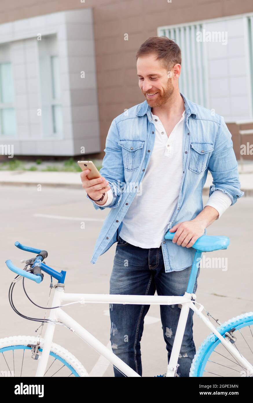 Casual guy next to a vintage bicycle with the mobile wearing denim ...
