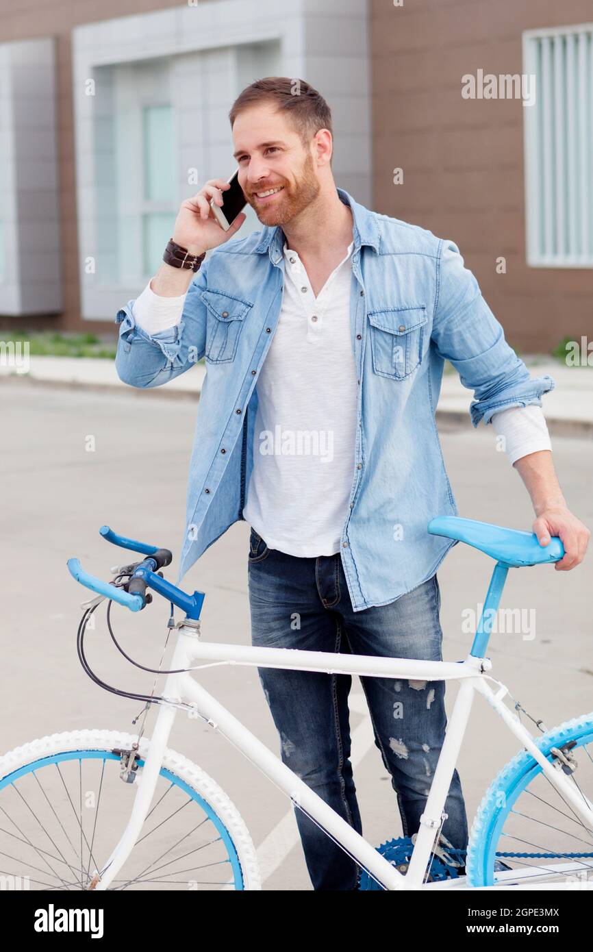 Casual guy next to a vintage bicycle with the mobile wearing denim ...