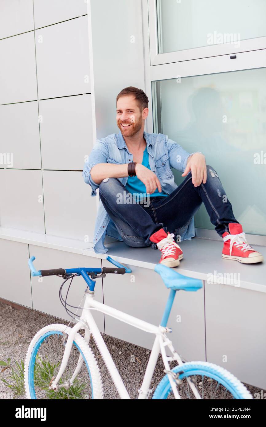 Pensive guy with denim shirt and beard next to his bike Stock Photo - Alamy