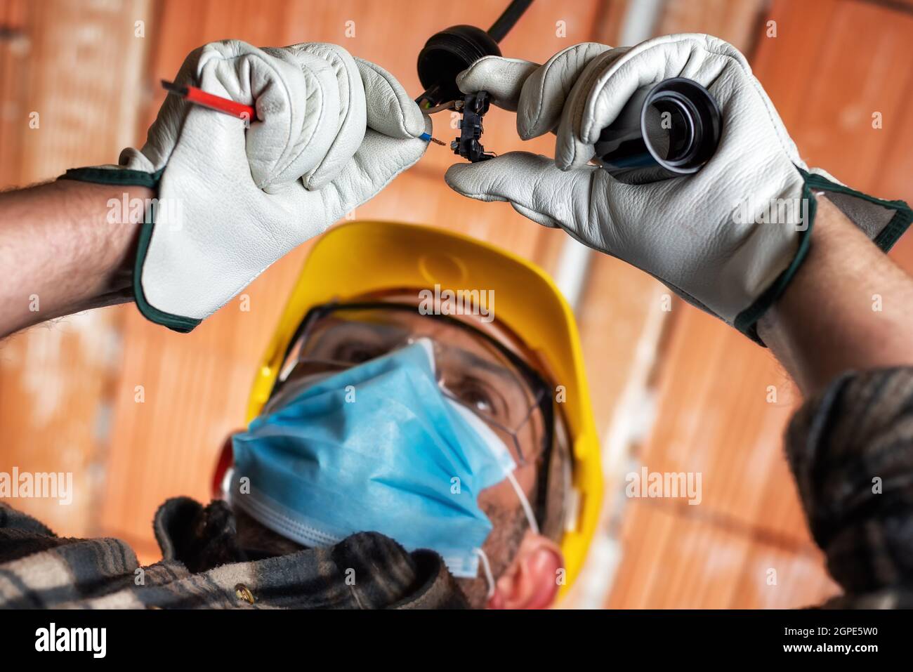 Electrician worker at work replaces the lamp holder protected by helmet ...