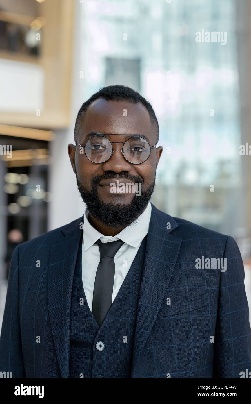 Happy African businessman in suit standing inside contemporary business ...