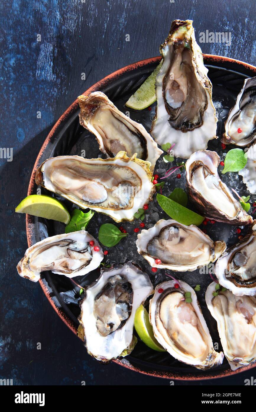Oyster season. Fresh oysters are placed on a round plate with ice and ...