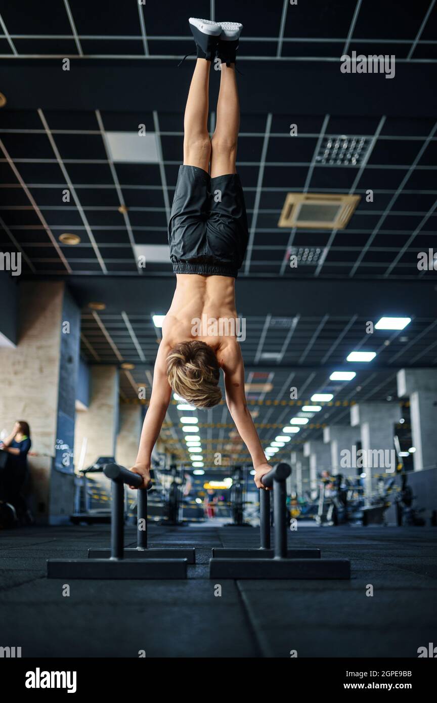 Athletic boy doing exercise on uneven bars in gym. Youngster on ...