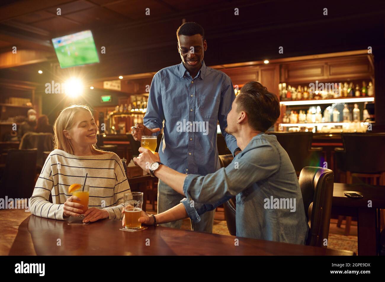 Three friends drinks alcohol and having fun at the table in bar. Group ...