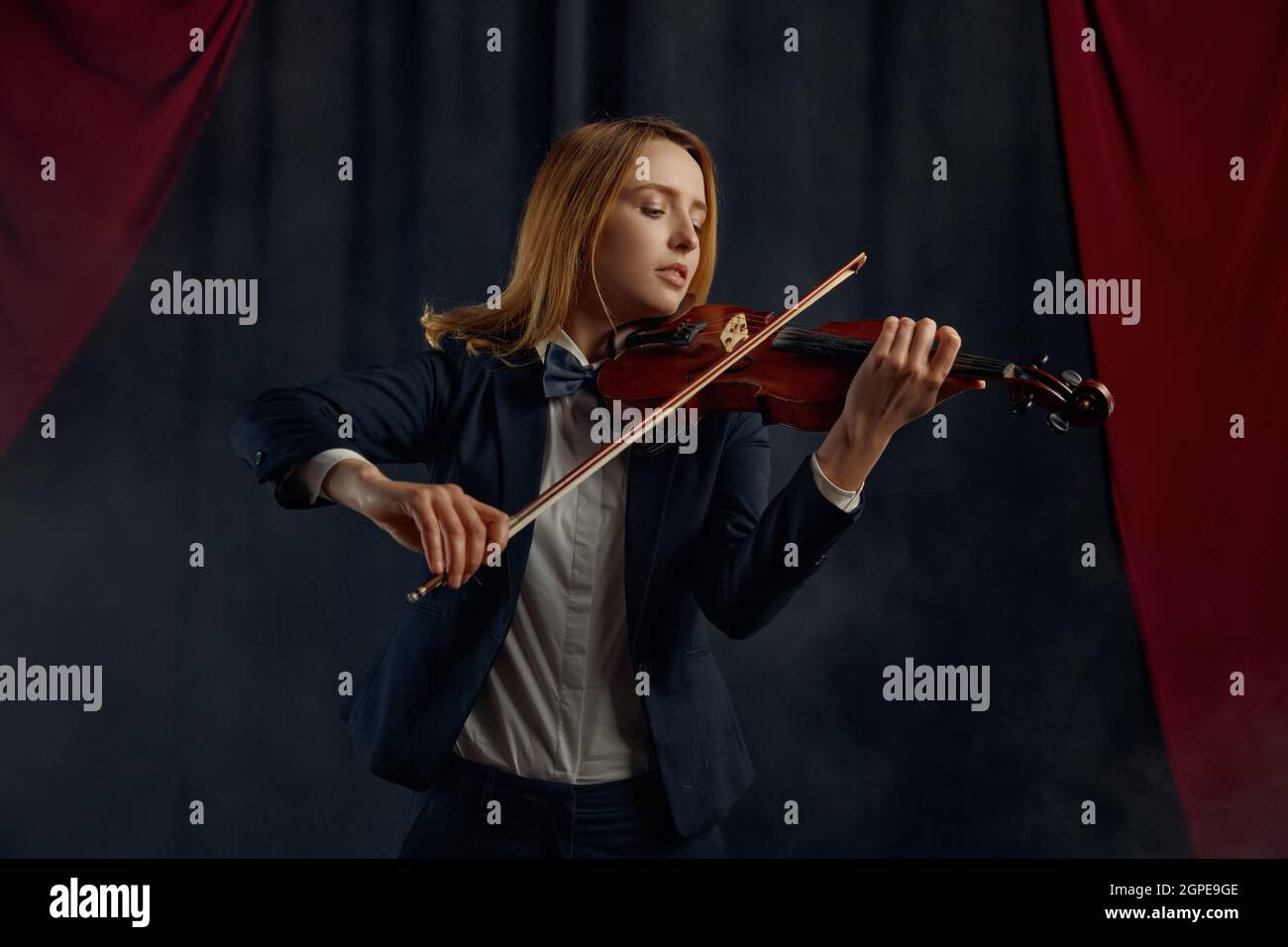 Female violonist with bow and violin, solo concert on stage. Woman with ...