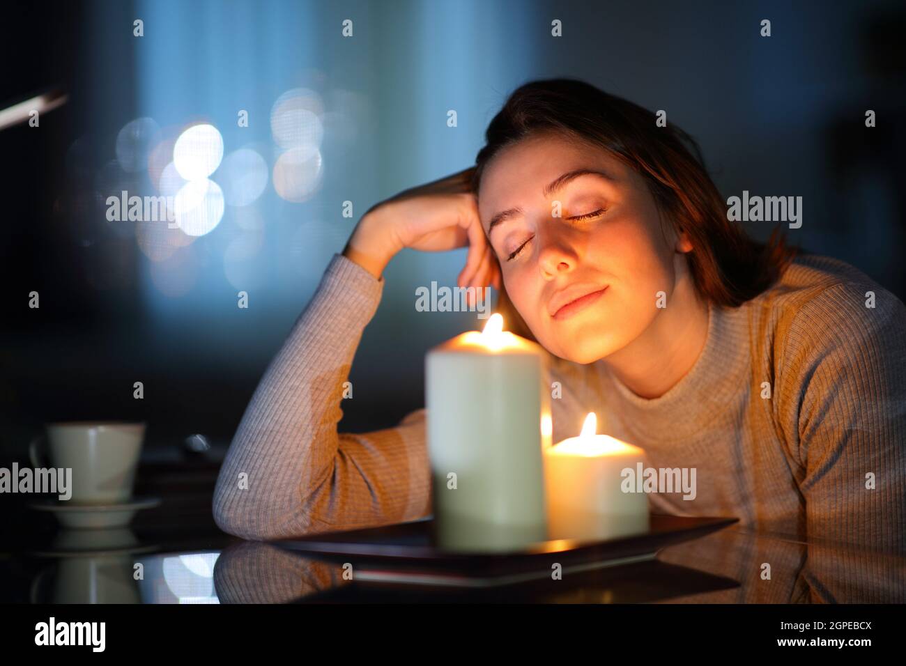 Relaxed woman smelling aromatic candles in the night in the living room ...