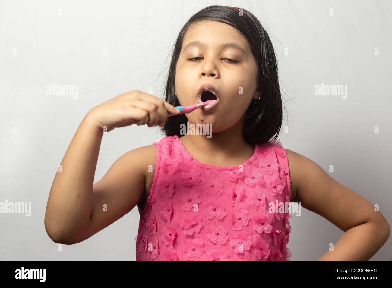 Portrait of an Indian girl child brushing teeth with toothbrush on ...