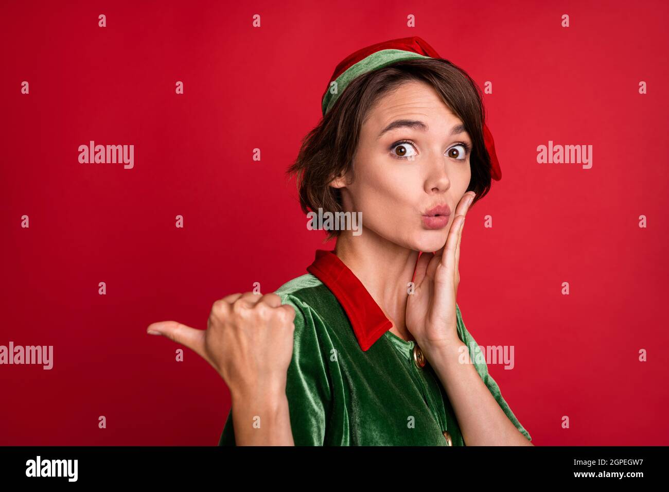 Photo of surprised lady direct thumb empty space palm cheek open mouth wear elf costume hat ...