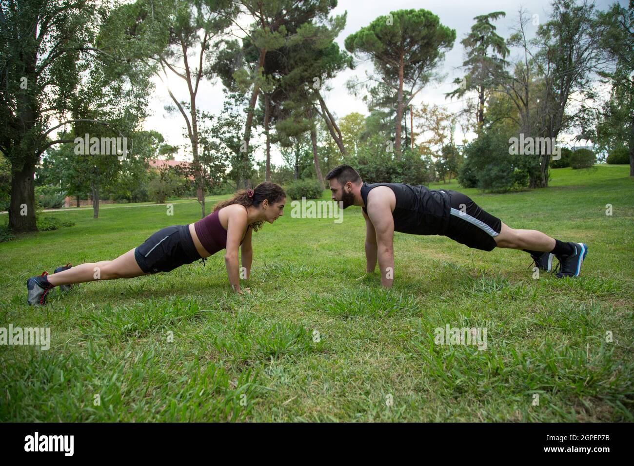 Young Caucasian man and woman couple practicing push-ups outdoor Stock ...