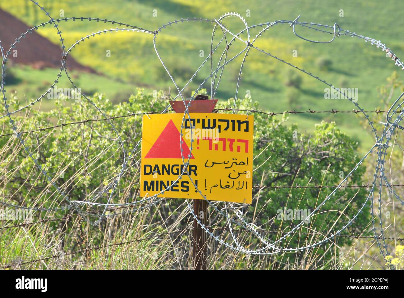 Minefield danger mines yellow warning sign on a barbed wire fence in ...