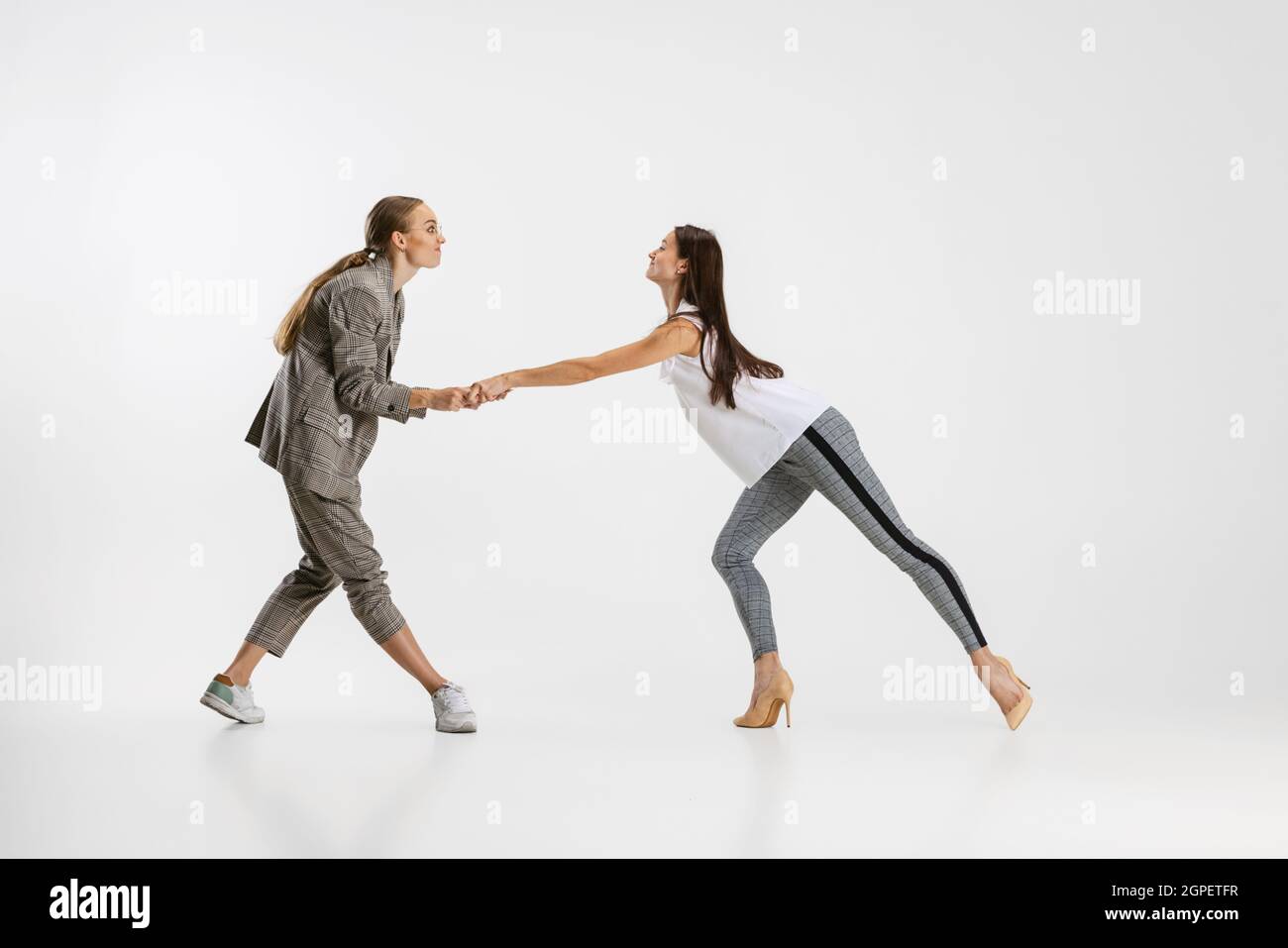 Two women, employees in casual clothes dancing isolated over white ...