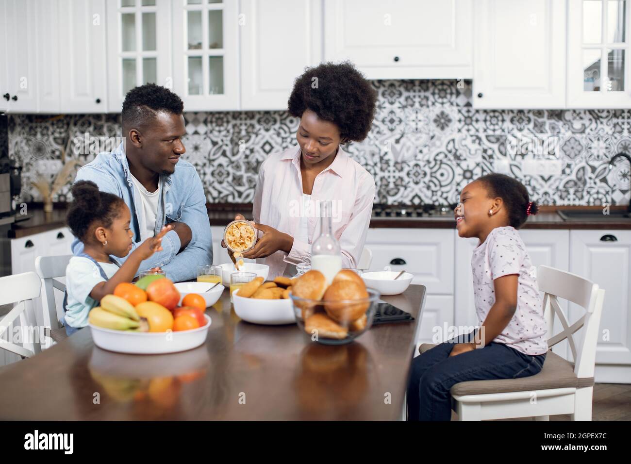 African american family of four eating cereals with milk during morning ...