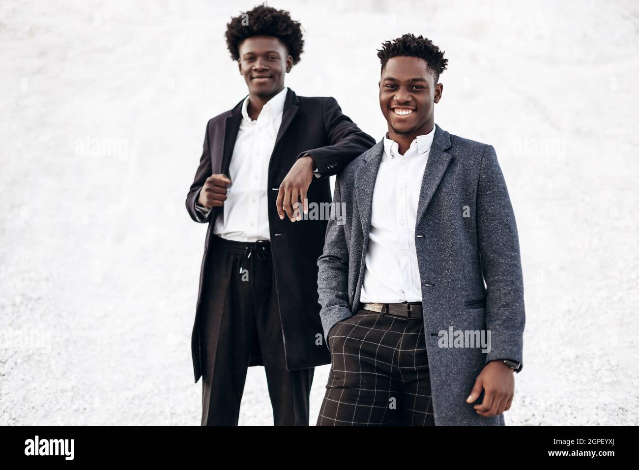 Two fashion models posing in the street, in classic clothes, suit, coat ...