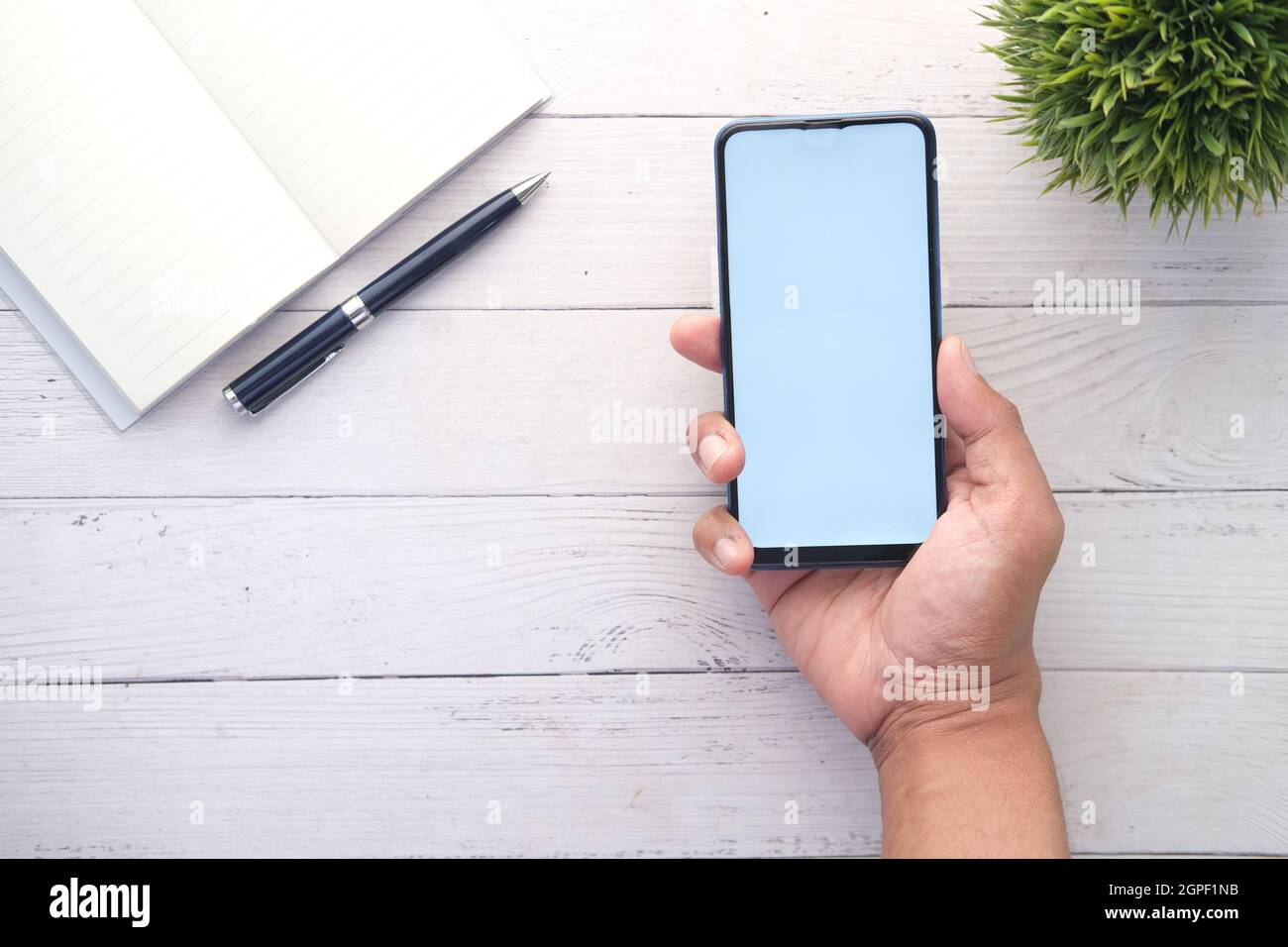 Top view of man hand holding smart phone with empty screen on office ...