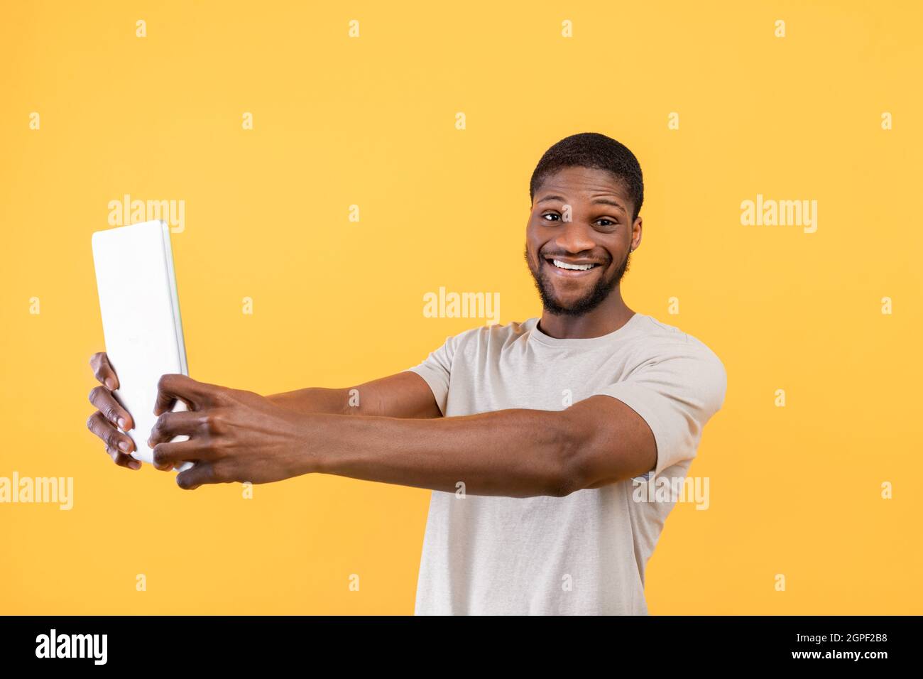 Cool game. Excited black guy holding digital tablet and looking at ...