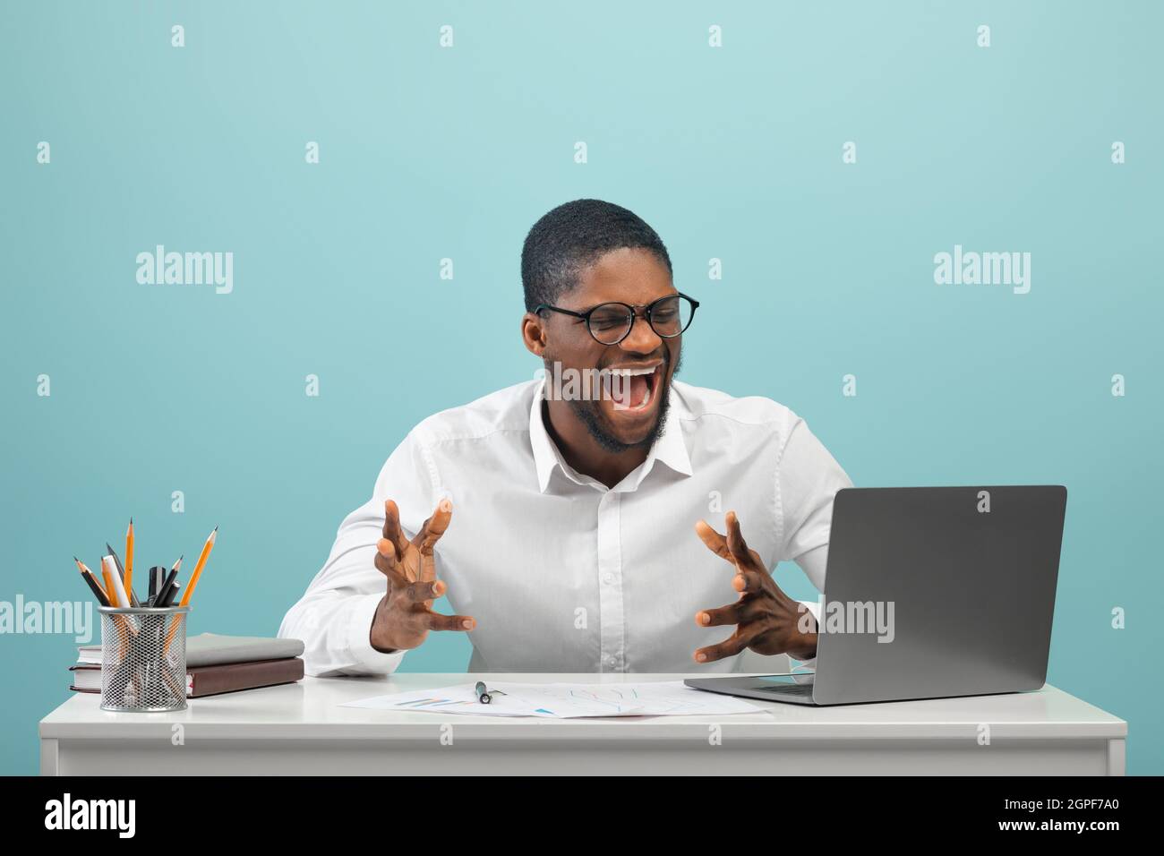 Frustrated black man sitting at desk with pc laptop and screaming over ...