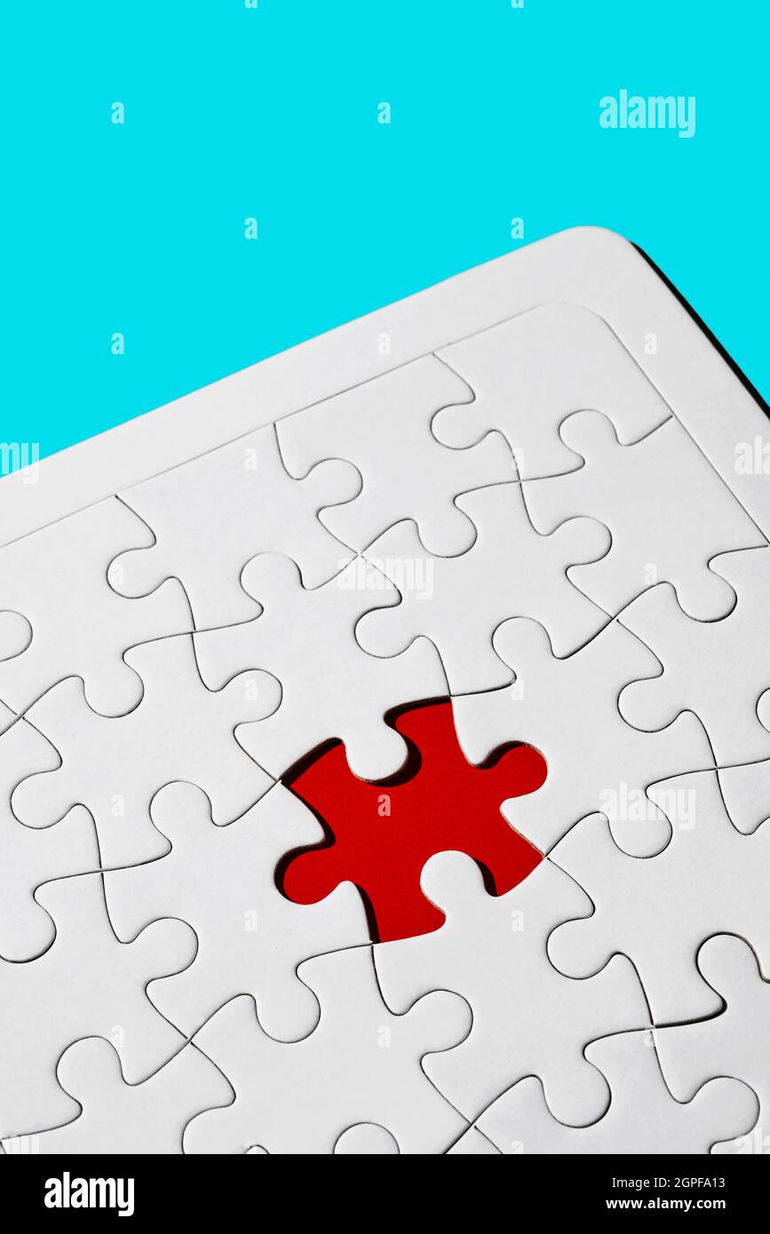 closeup of a red gap in a blank white jigsaw puzzle missing a piece on ...