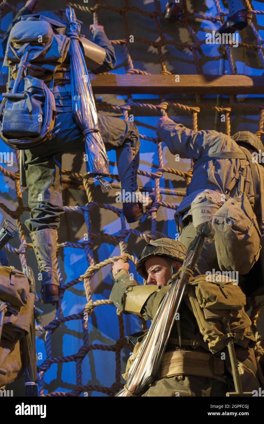 Soldiers climbing down a rope ladder onto a Higgins landing craft ...
