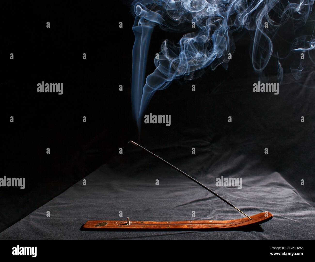 indian incense stick with smoke on black background indoor closeup ...