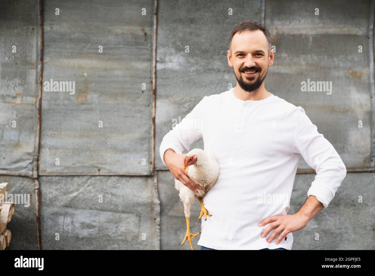 Portrait of farmer carrying chicken against grey wall Stock Photo - Alamy