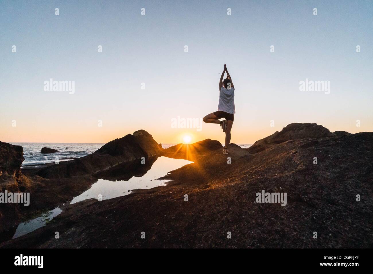 a person standing doing yoga in a sea landscape against sunset Stock ...