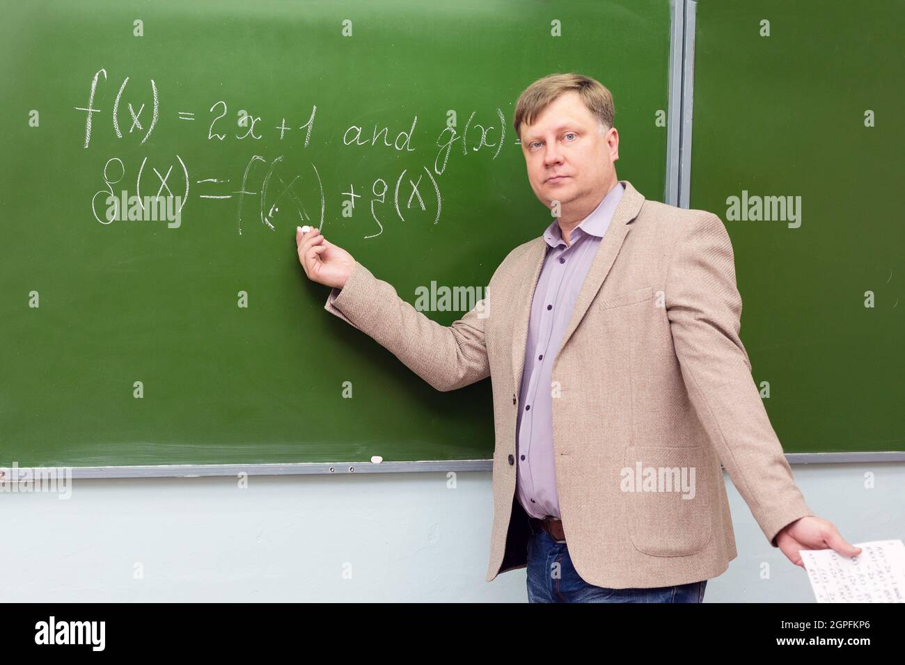 A strict math teacher at the blackboard explains the solution of the ...