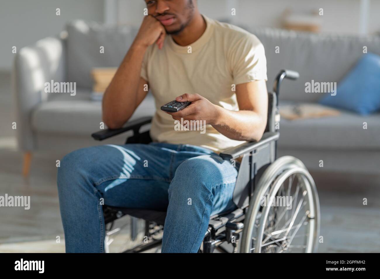 Bored disabled black man in wheelchair watching dull movie on TV ...