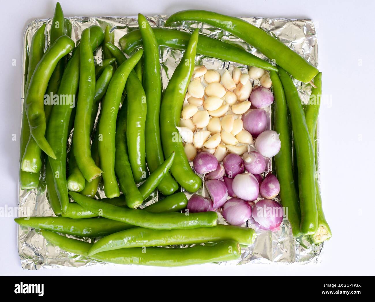 Top view of raw green chilli, garlic and onion on aluminum foil tray ...