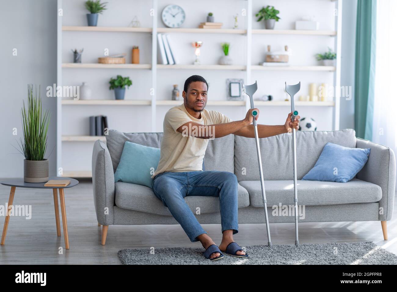 Full length of millennial black guy having difficulty standing up from ...