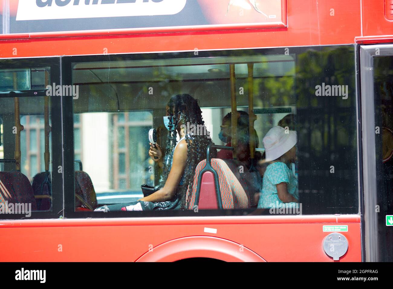 A passenger wearing a mask attempts to cool off with a small electric ...