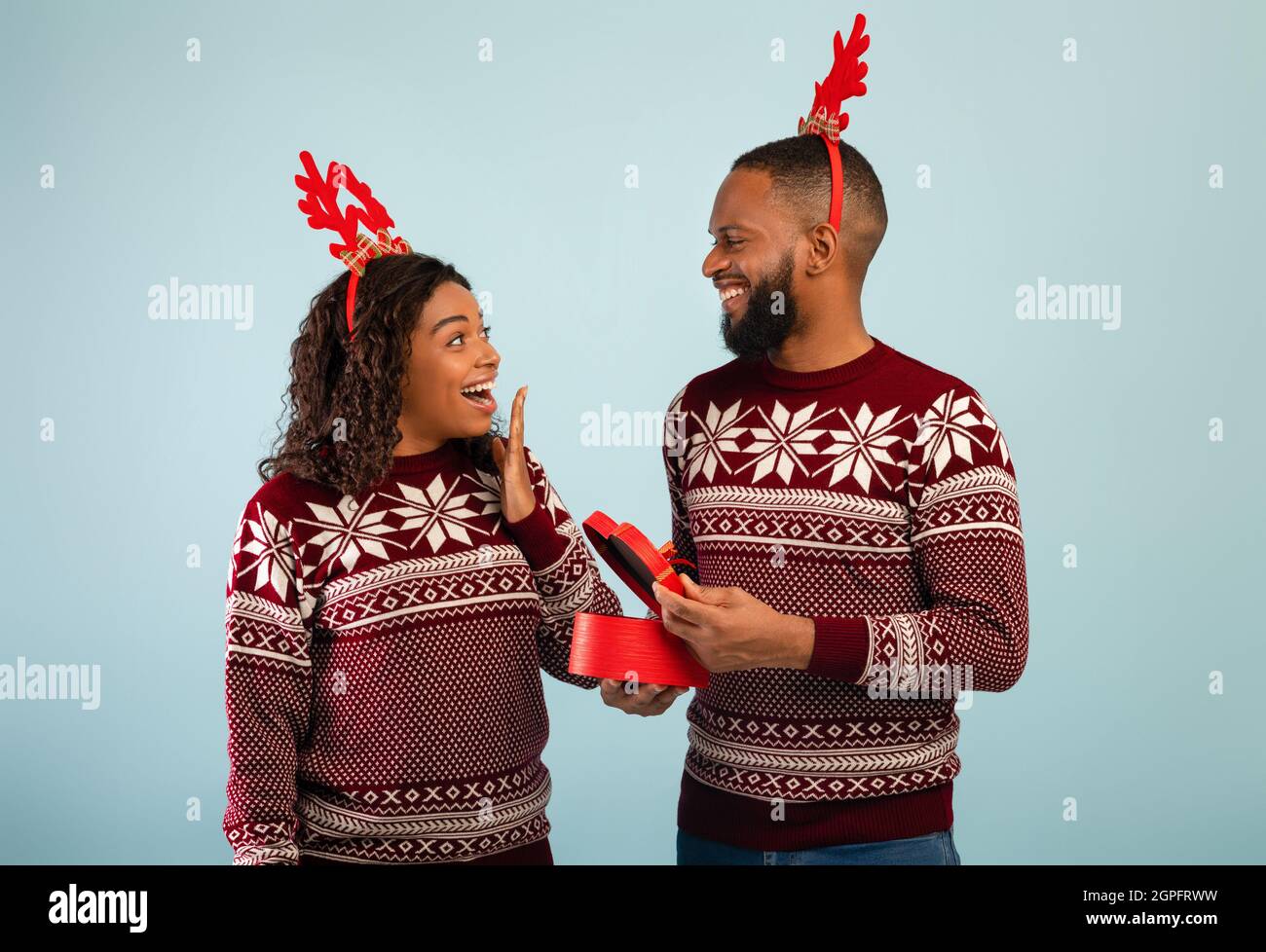 Happy black man giving gift box to surprised wife and celebrating New ...
