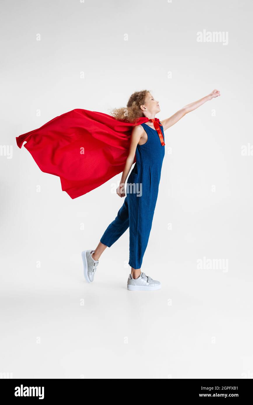 Portrait of beautiful caucasian little curly girl wearing red cape ...