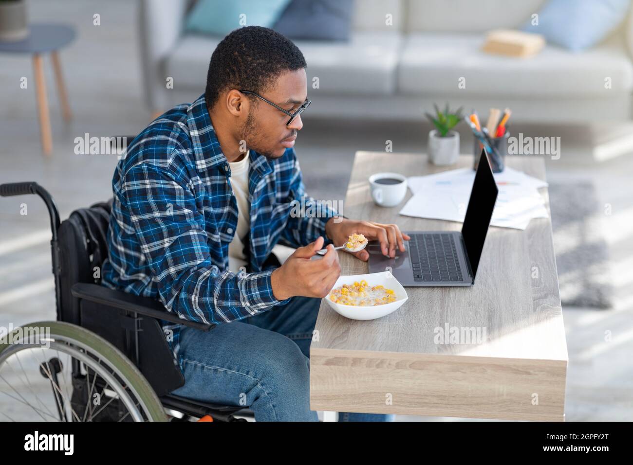 Handicapped black man in wheelchair using laptop for online job and ...