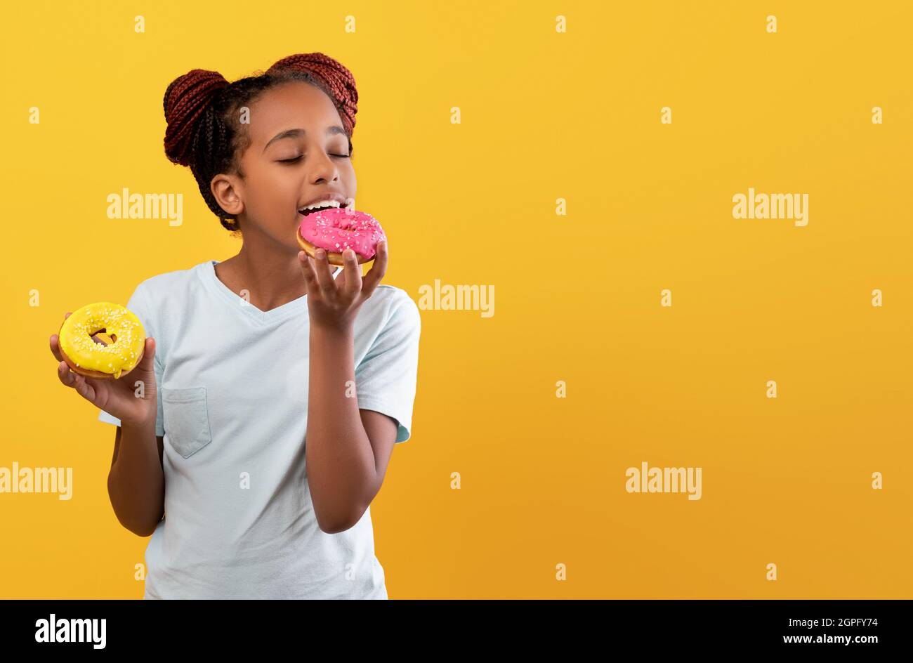 Pretty black girl holding delicious colorful donuts Stock Photo - Alamy