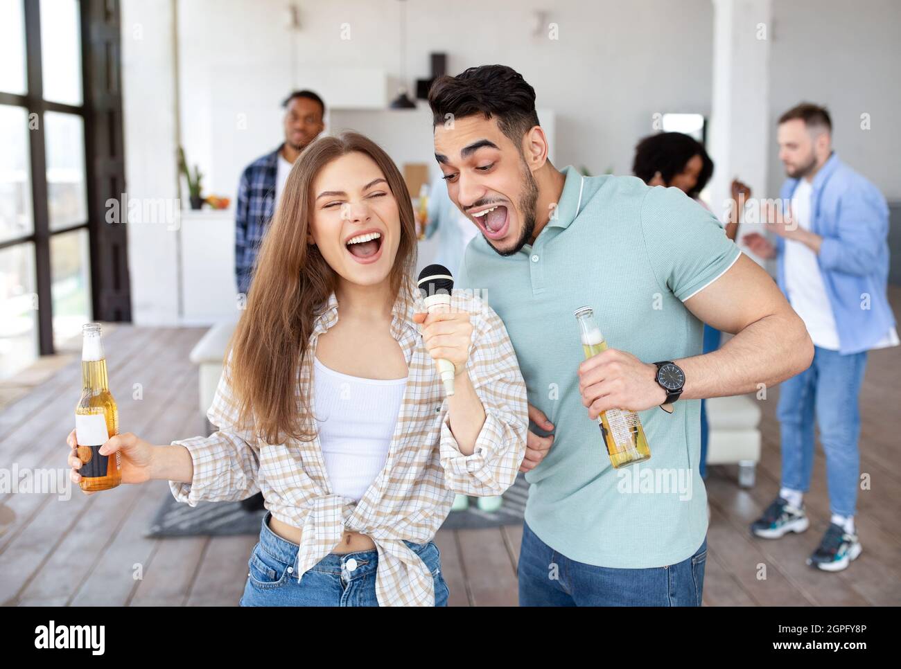 Young Interracial Couple Singing Song Together Into Microphone Holding