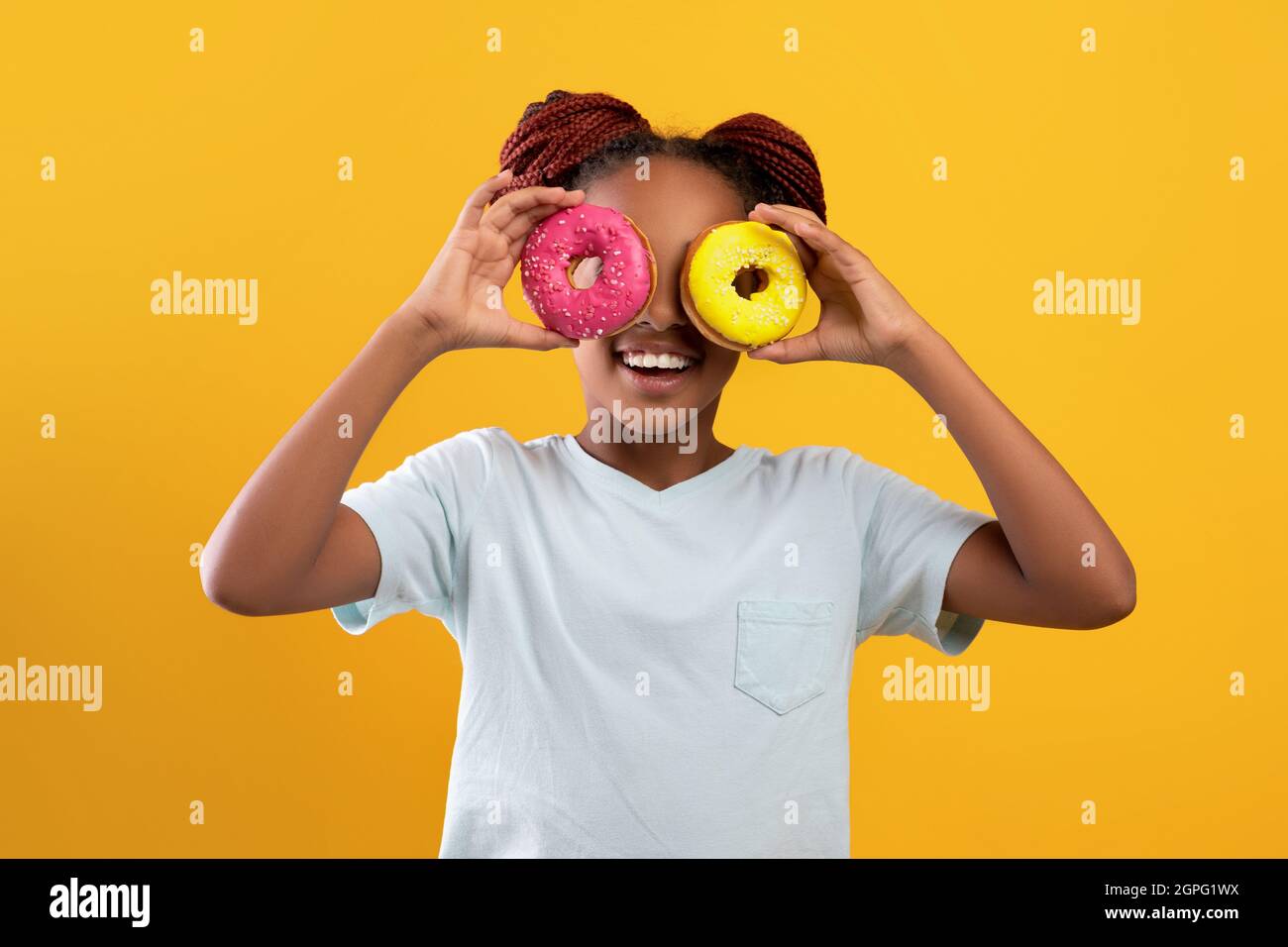 Funny afro american teen girl holding donuts over eyes Stock Photo - Alamy
