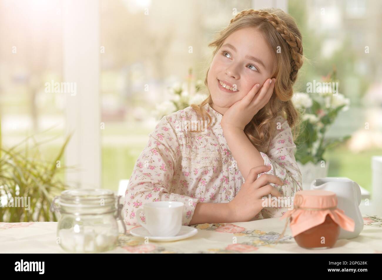 Smiling little girl holding big cup of tea Stock Photo - Alamy