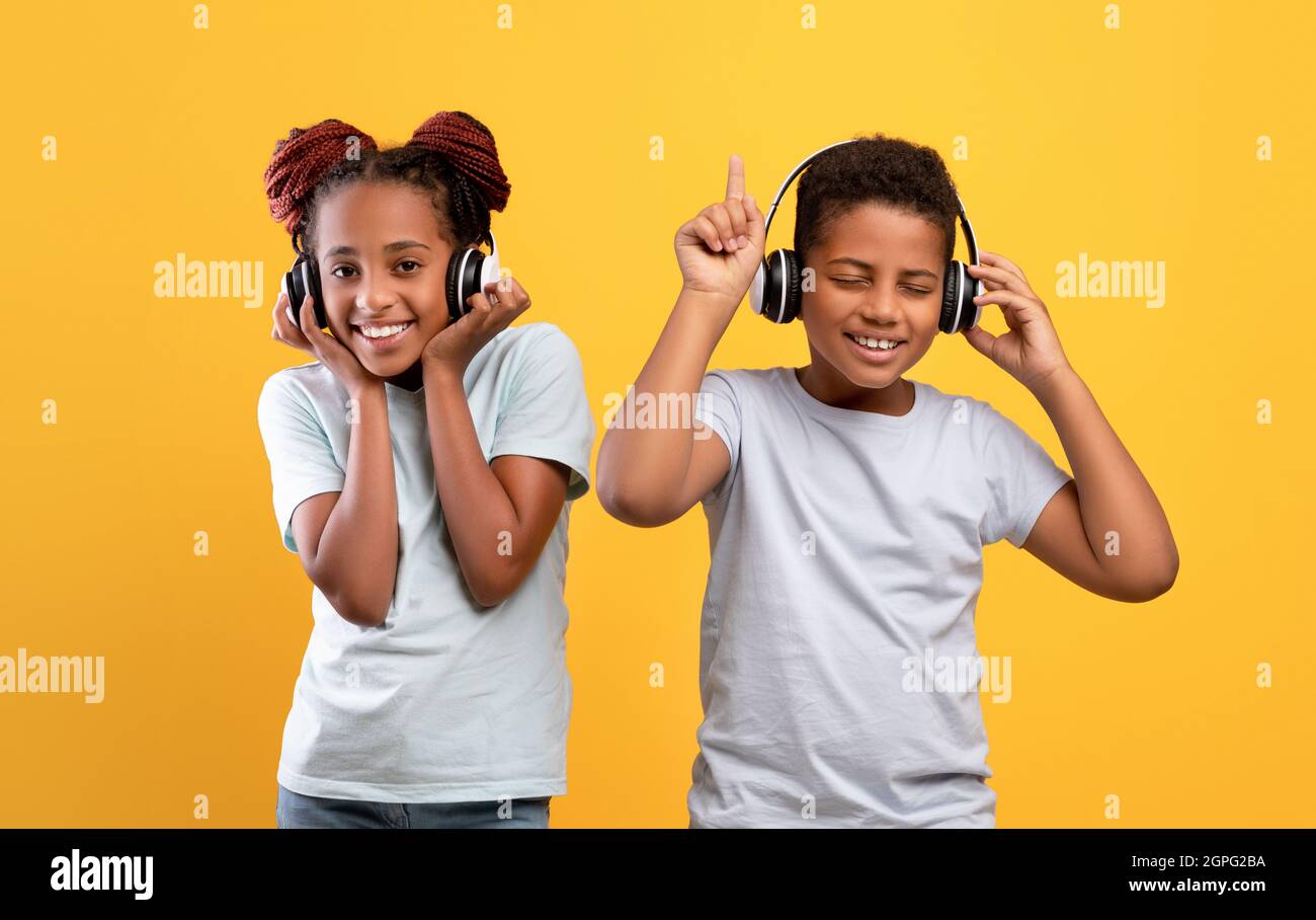 Emotional black siblings with wireless headsets listening to music ...