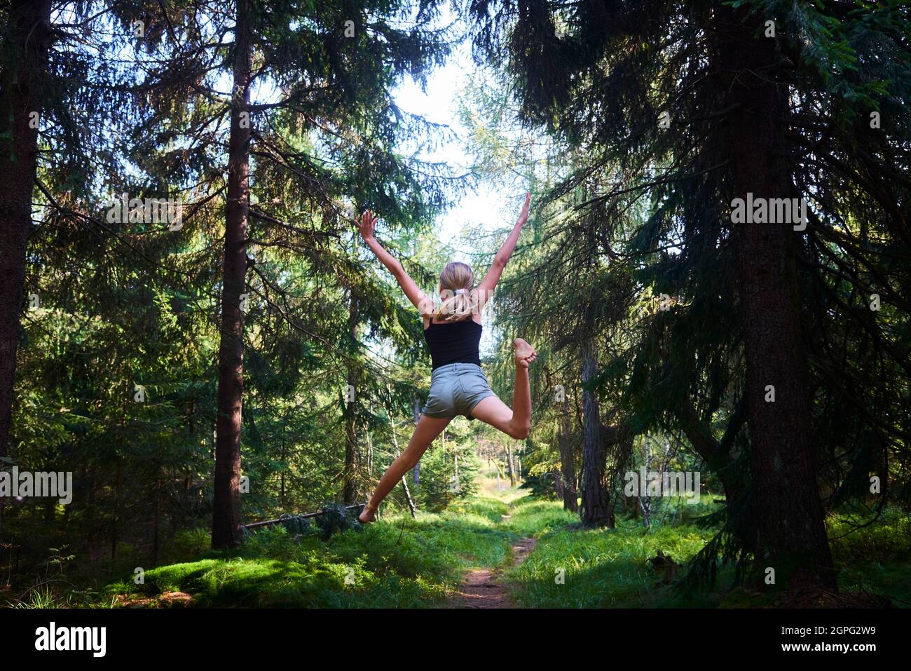 Young girl flying in the air in the woods. Jumping for freedom Stock ...