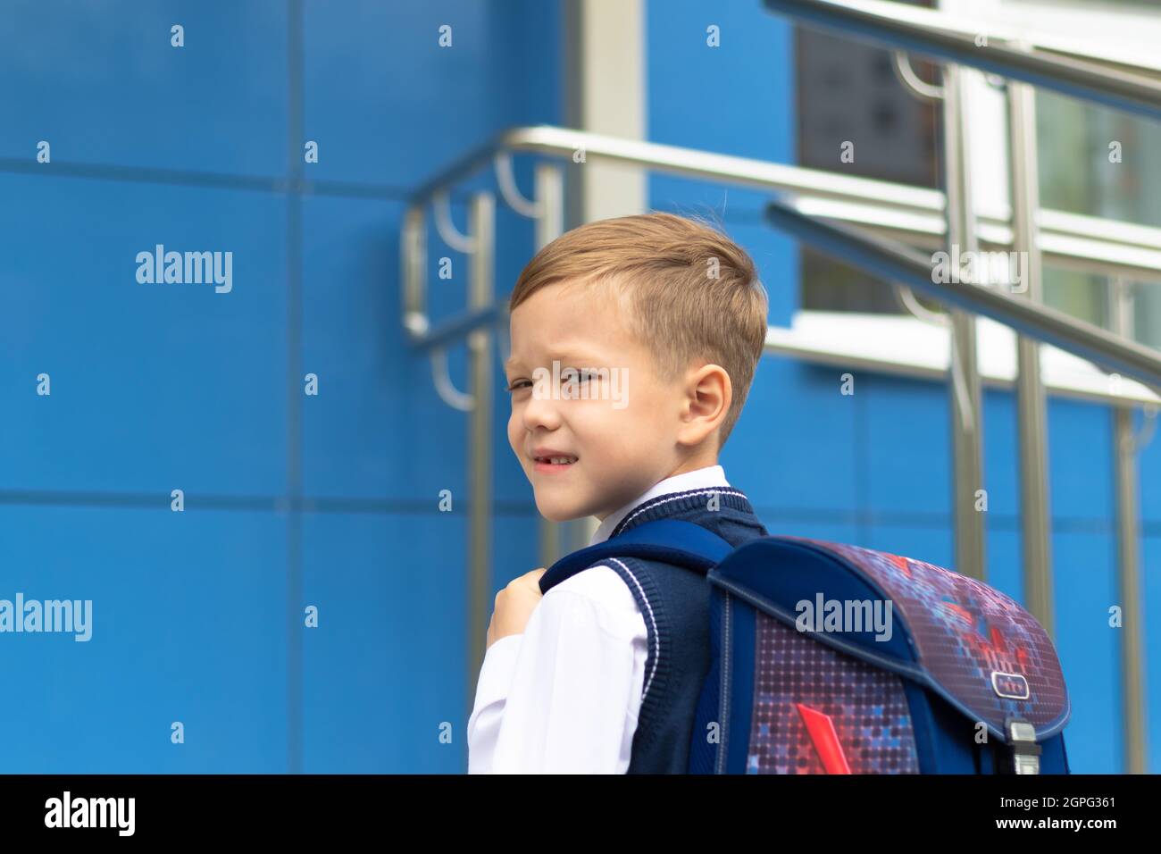 A cute first grader boy in a school uniform with a schoolbag goes to ...