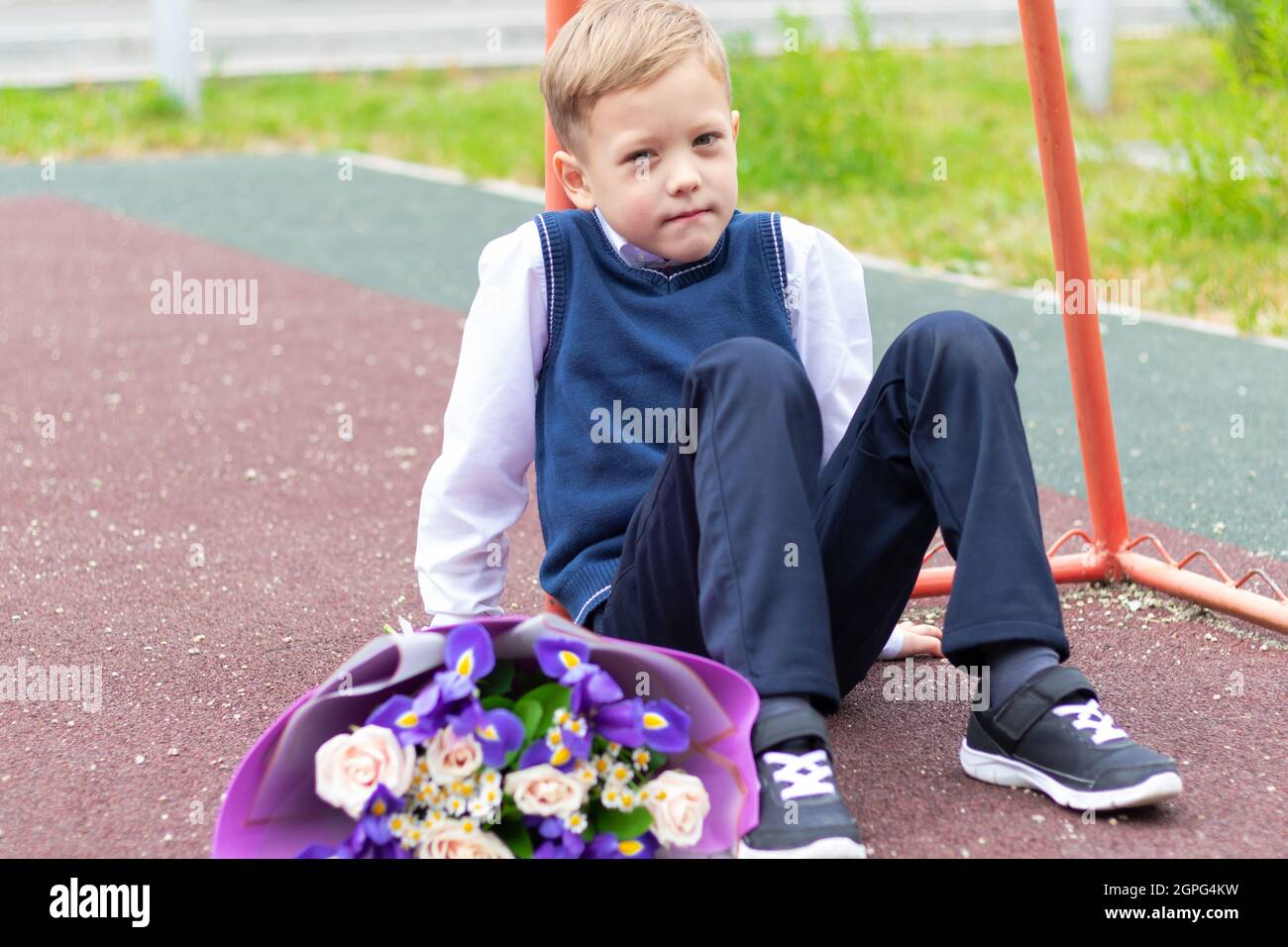A cute first-grader boy in a school uniform with a beautiful bouquet of ...