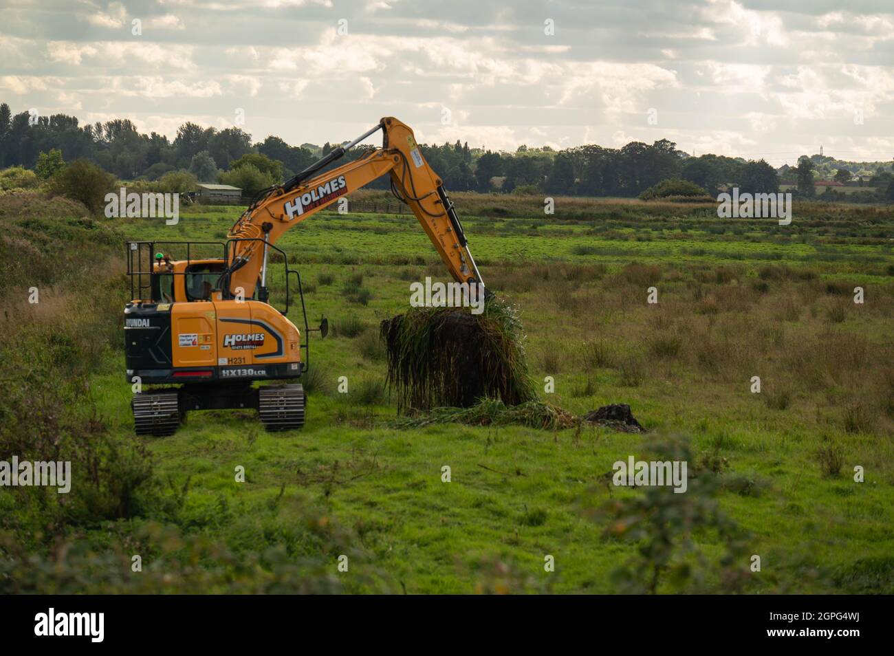 A digger maintaining drainage ditches on low-lying grazing marsh on the ...