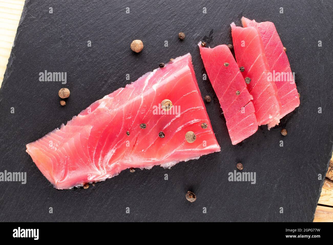 One piece of slightly salted tuna meat on a slate stone, close-up, top ...