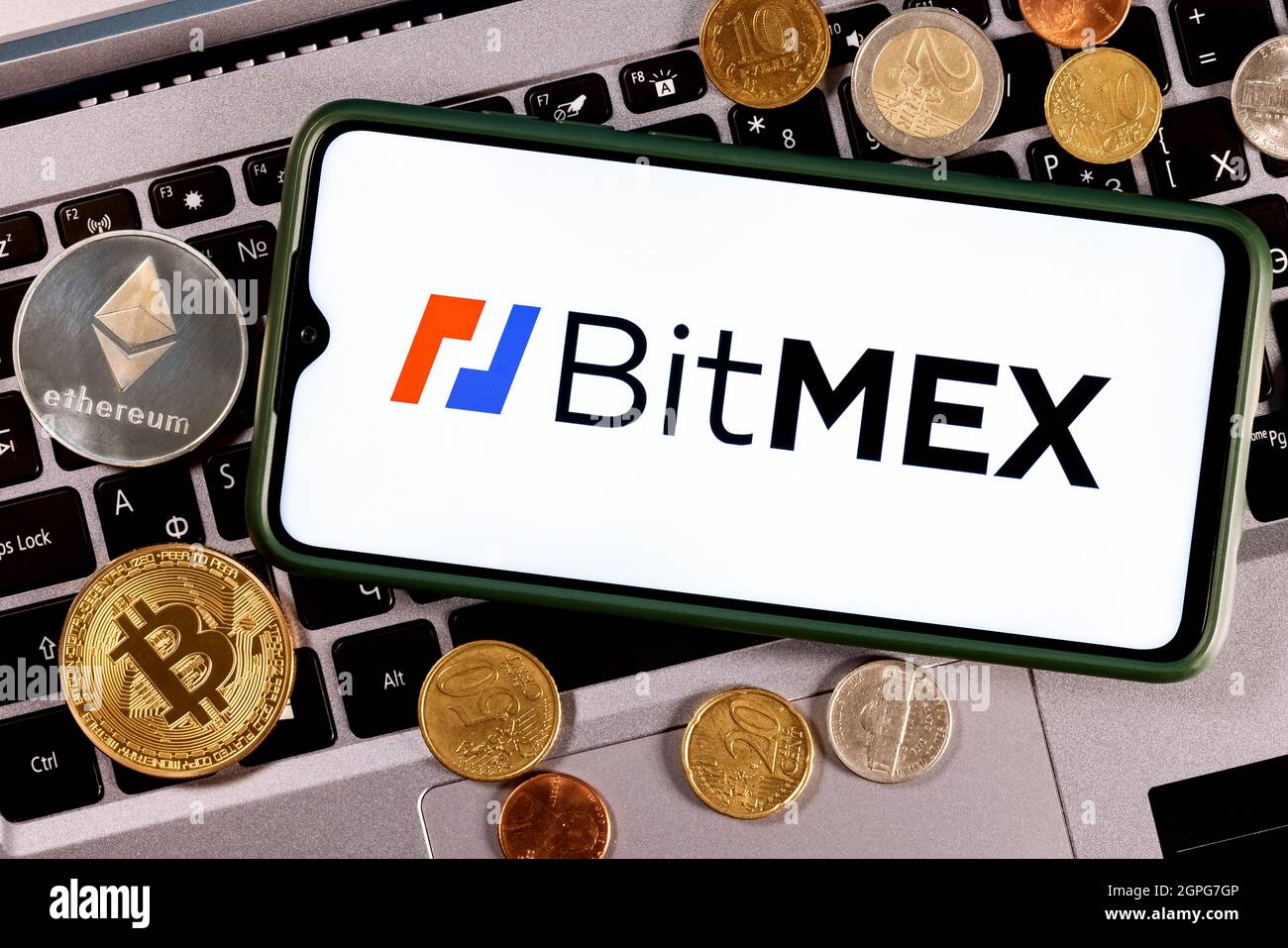 A smartphone with the BitMEX logo surrounded by different coins on the ...