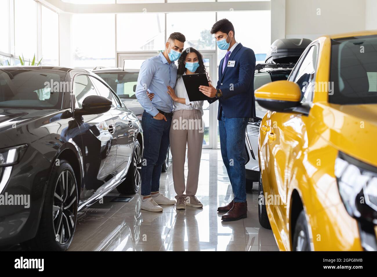 Young couple embracing while having conversation with salesman, buying ...