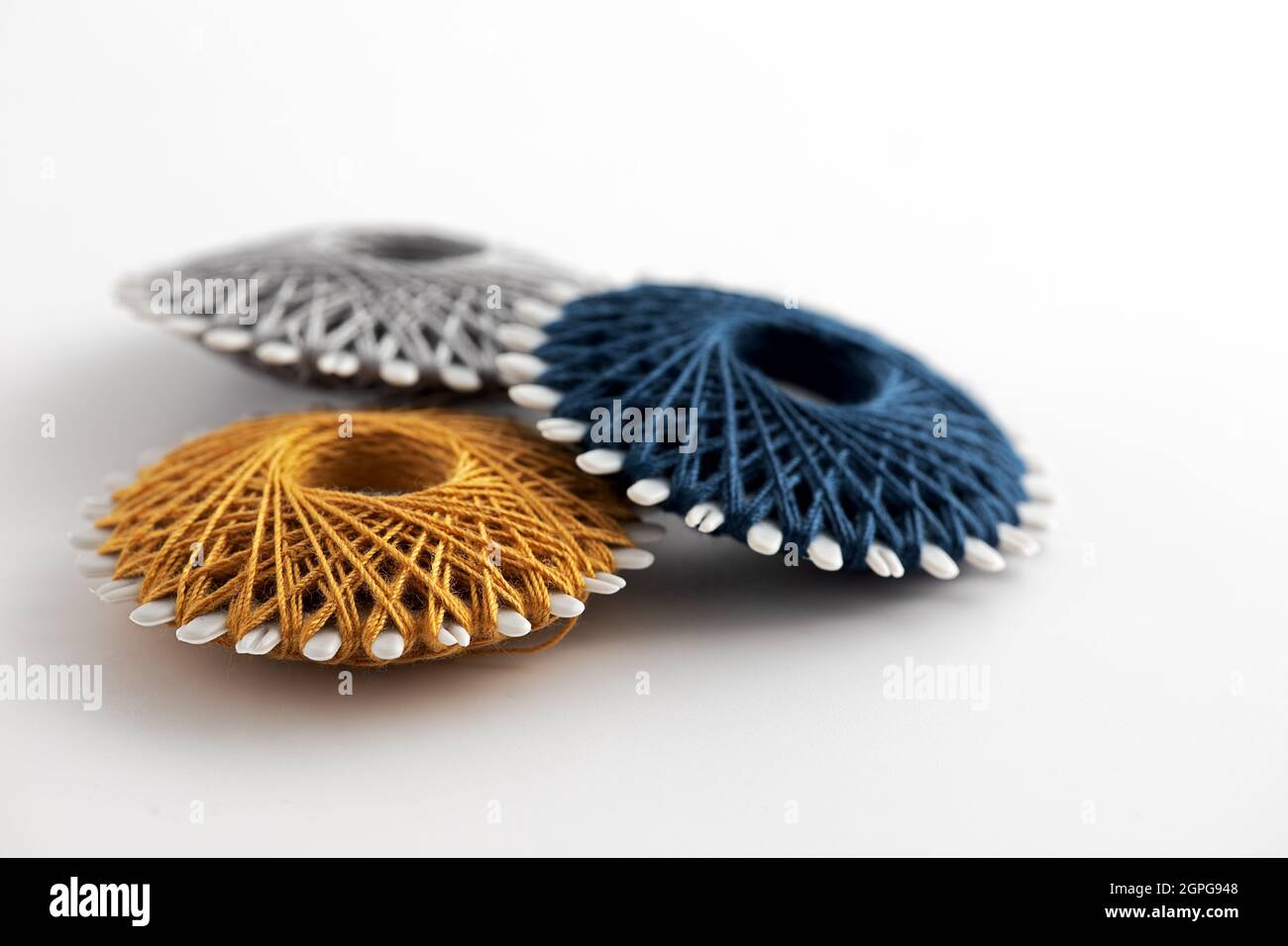 gray, blue and yellow sewing thread on round bobbins isolated on white ...