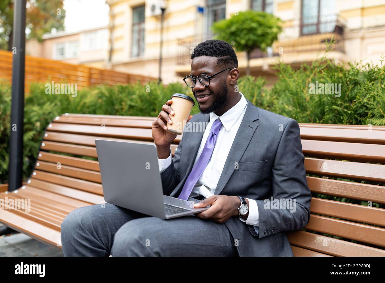Corporate african american executive in formal wear sitting on bench ...