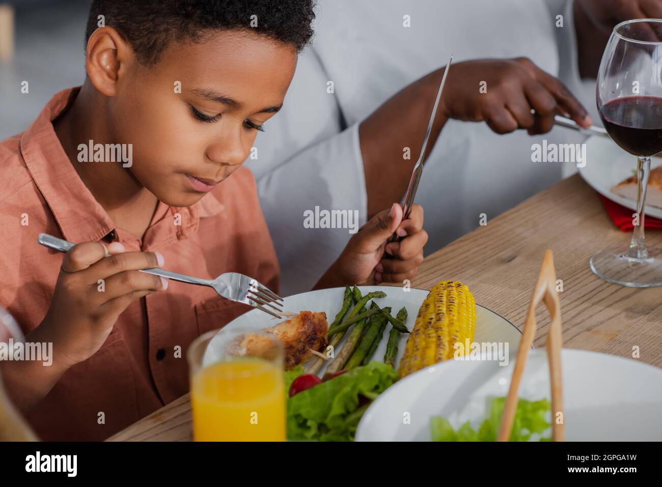 african american boy having thanksgiving dinner near blurred granny ...
