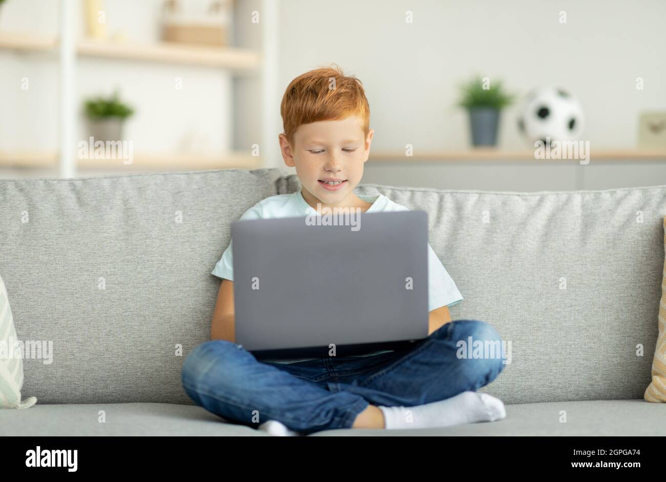 Redhead child using laptop, playing online video game Stock Photo - Alamy