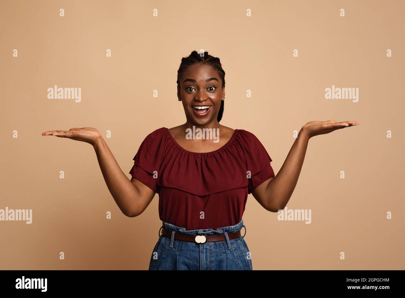 Confused afro-american woman holding something invisible on both palms ...